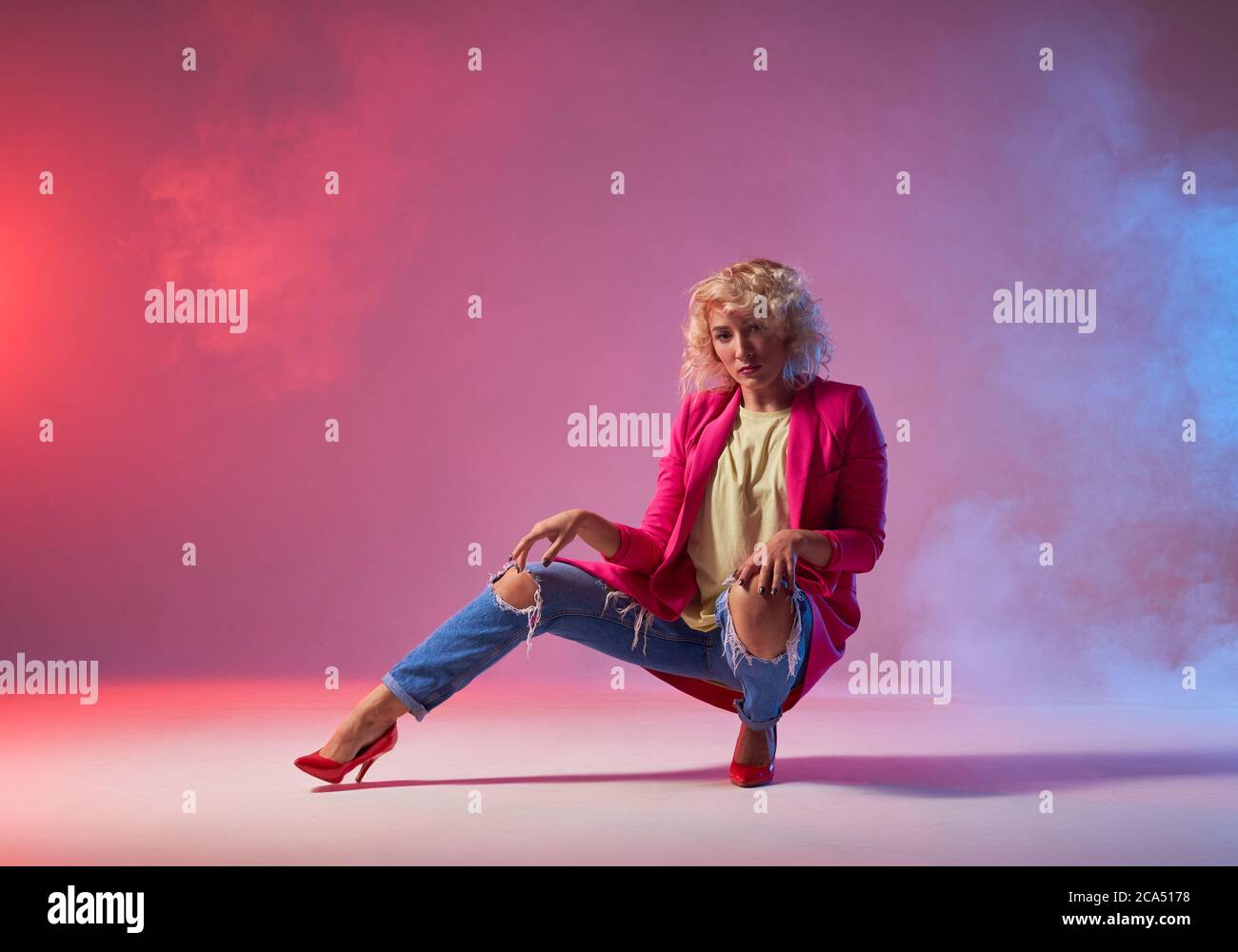 Serious young dancer waiting beginning of performance, sitting on squat ...