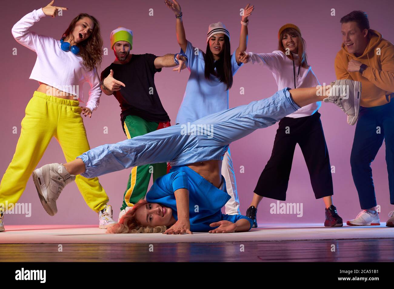 Sportive professional hip hop dancer, standing upside down, doing split ...