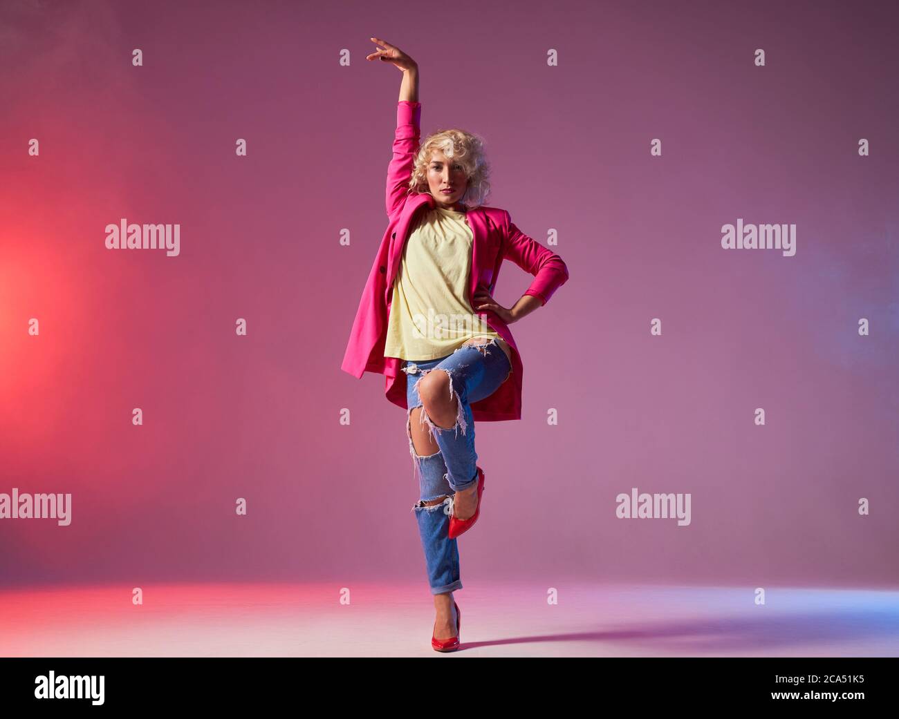 Attractive blonde woman with long wavy hair balancing on one leg ...