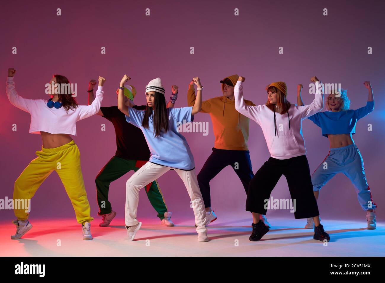 Active young group of people standing synchronically on floor of studio ...