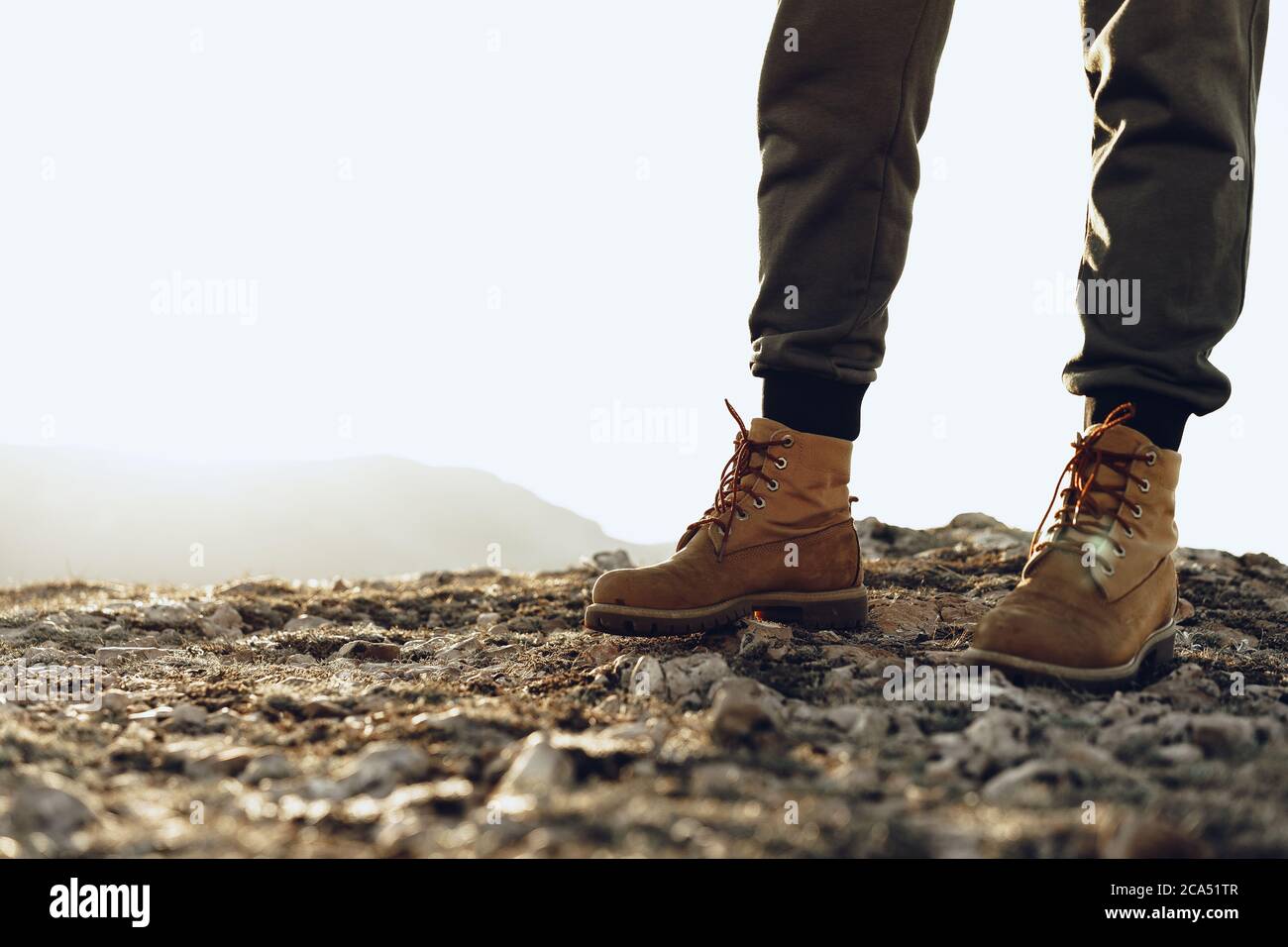 Legs of a backpacker in hiking boots standing on the top of the ...