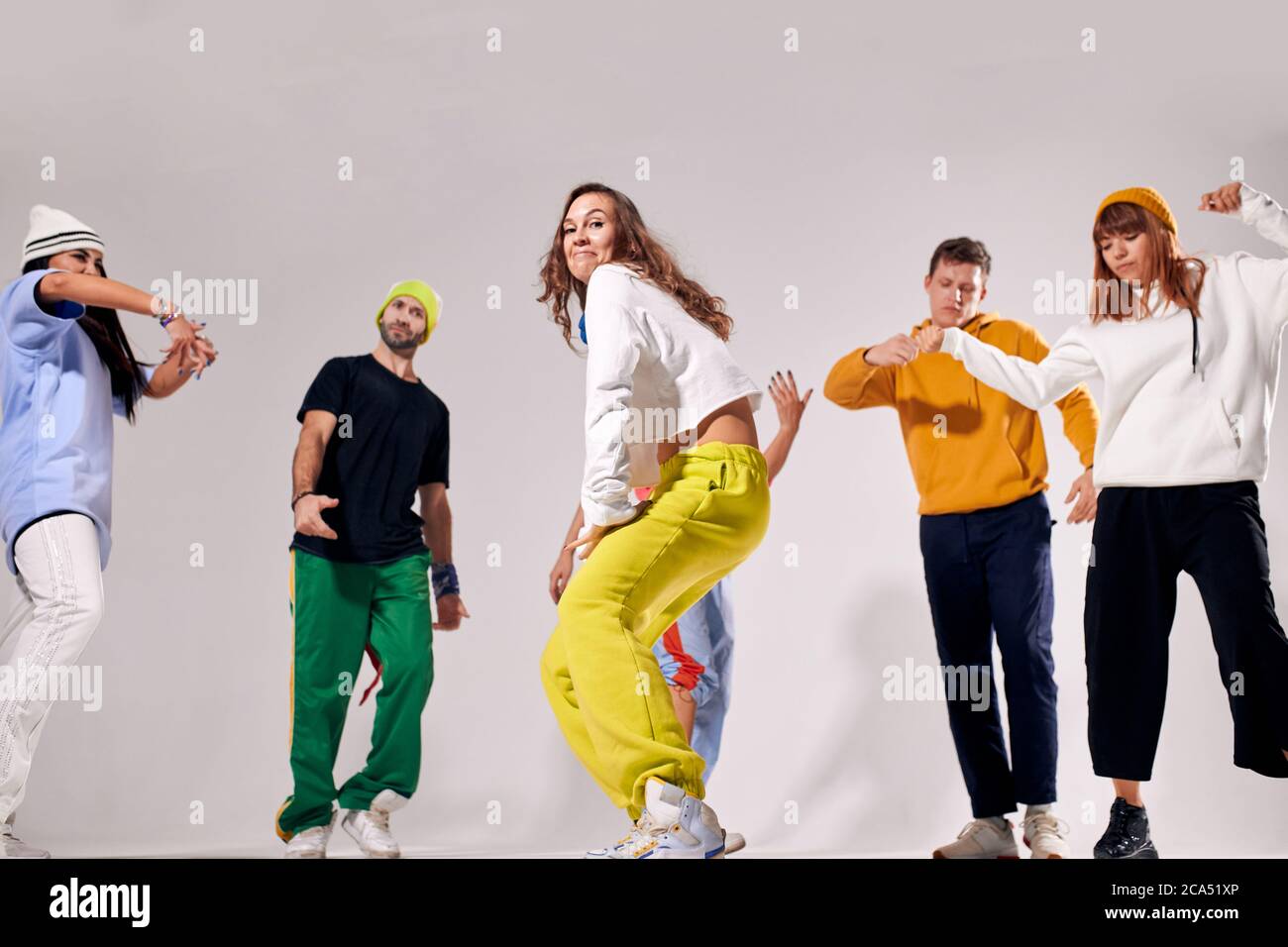 Funny young lady standing sideways towards camera, turning head at ...