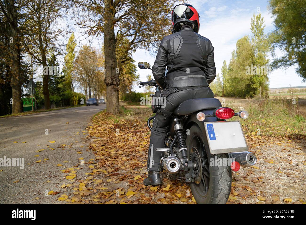 Rear view of a biker girl parked on the side of the road Stock Photo ...