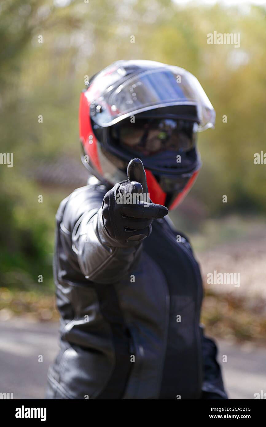 Biker girl pointing his finger at you. Soft focus background Stock ...