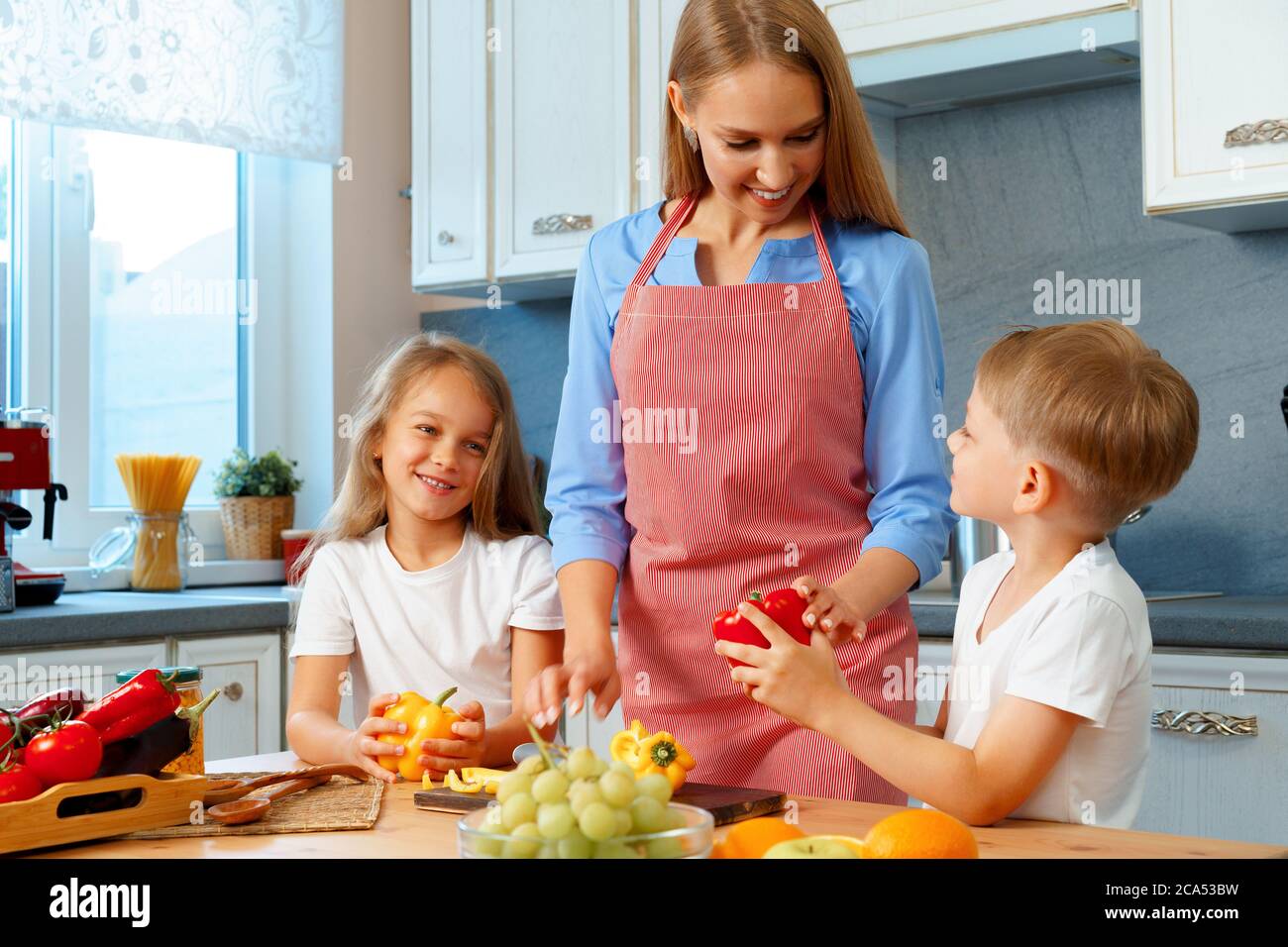 Mother cooking with her children in kitchen Stock Photo - Alamy