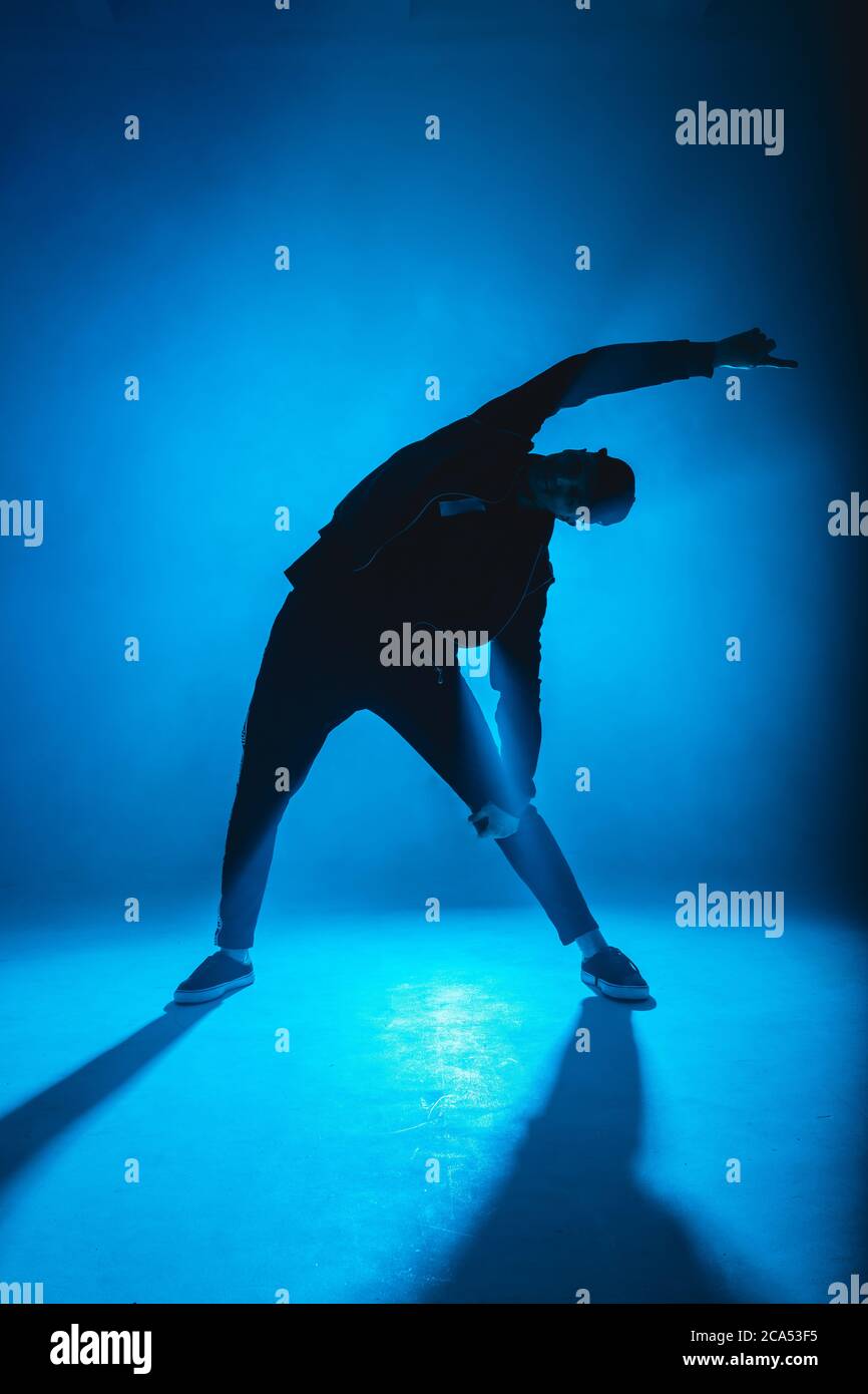 Full-size of silhouette of male break dancer performing on blue neon ...