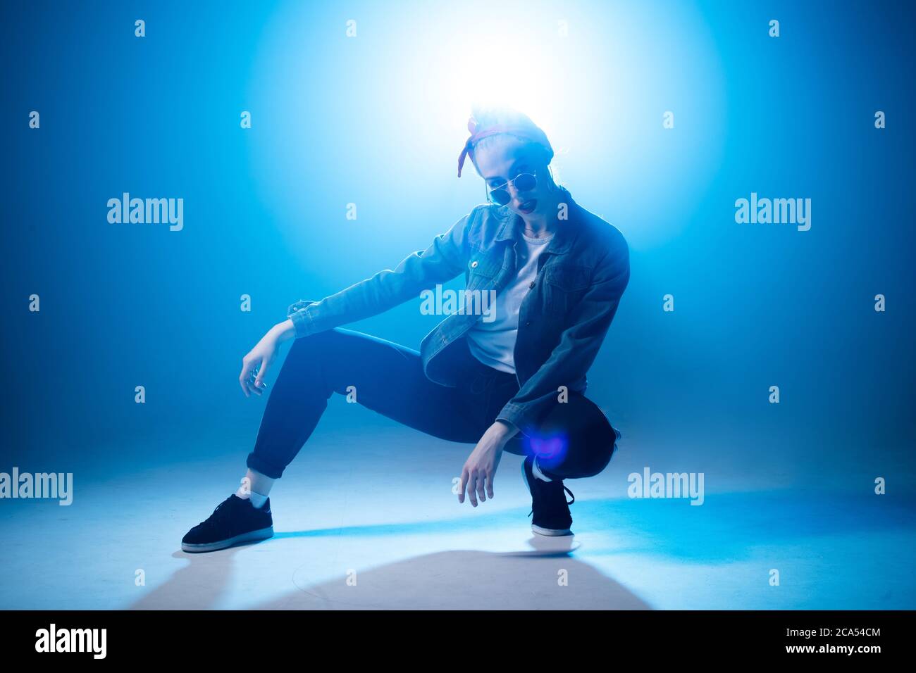 Young hip-hop female dancer performing solo on the stage in blue neon ...
