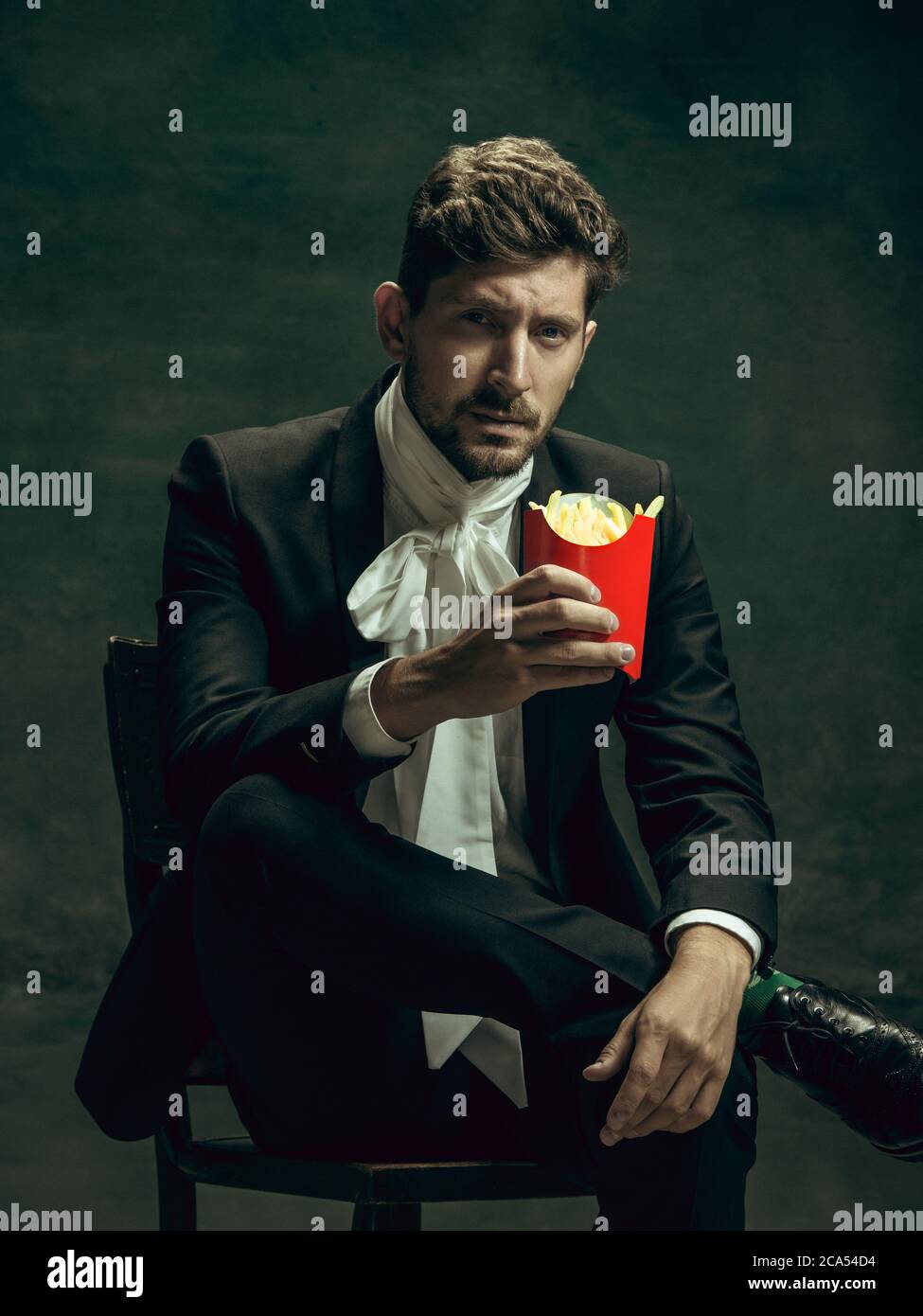 Enjoy urban food. Young man in suit as Dorian Gray isolated on dark ...