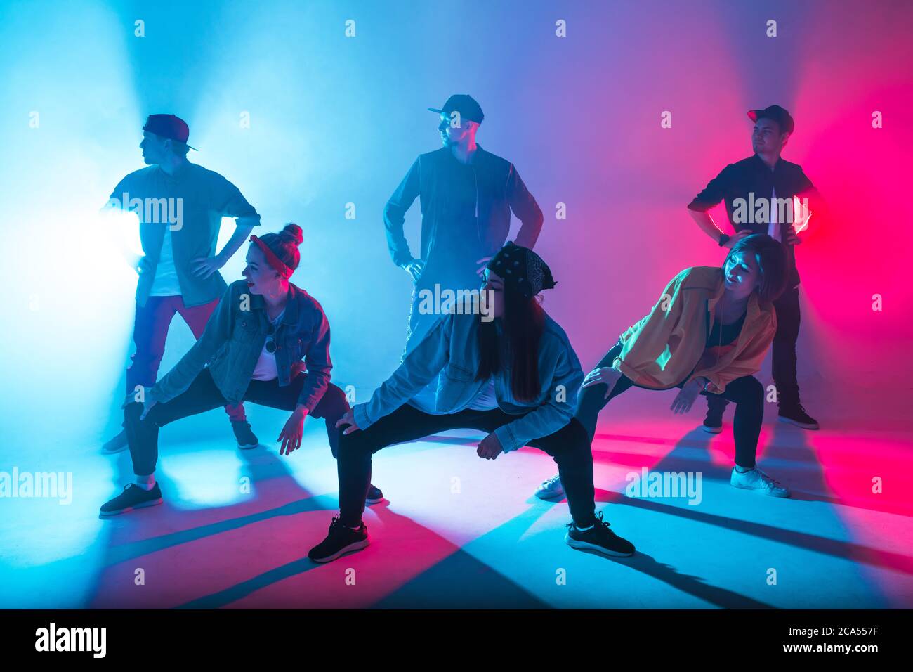 Group of diverse young hip-hop dancers in studio with special lighting ...
