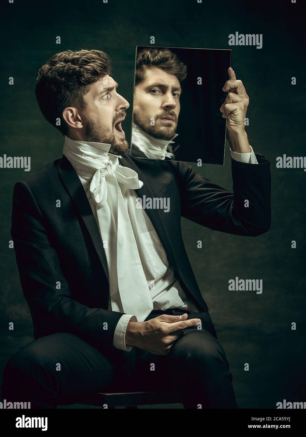 Scaring portrait. Young man in suit as Dorian Gray isolated on dark ...