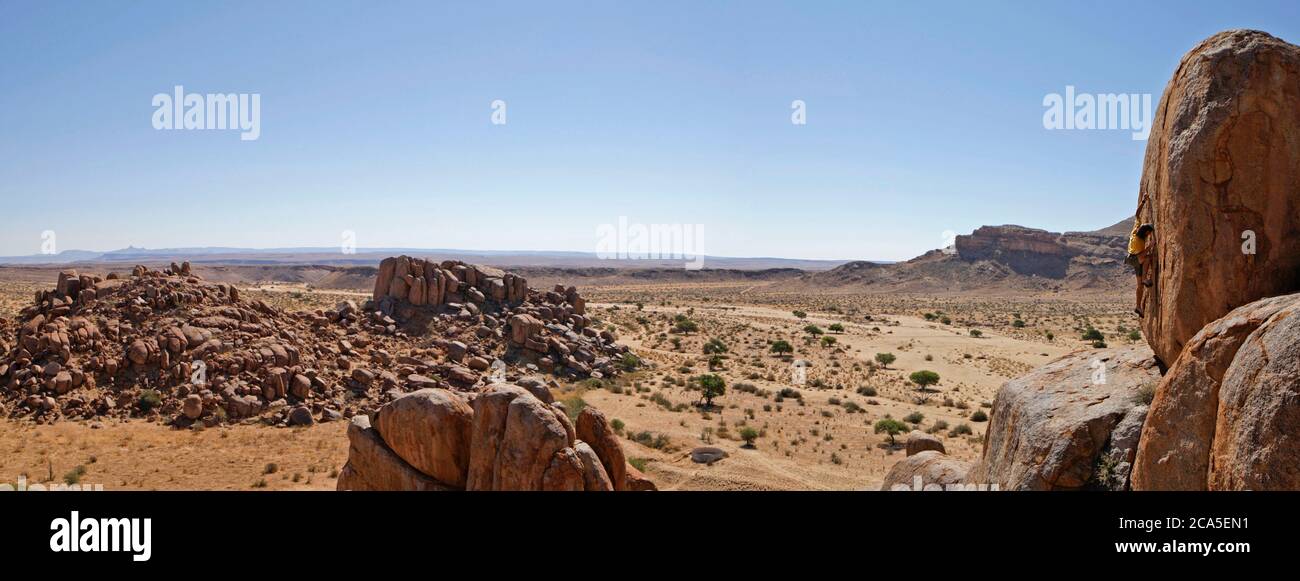 Namibia, Erongo Province, Spitzkoppe, climbing a boulder in the desert ...