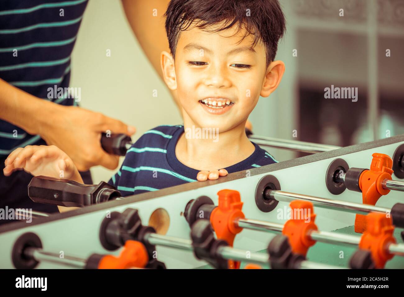 Happy kid playing foosball table with family Stock Photo - Alamy