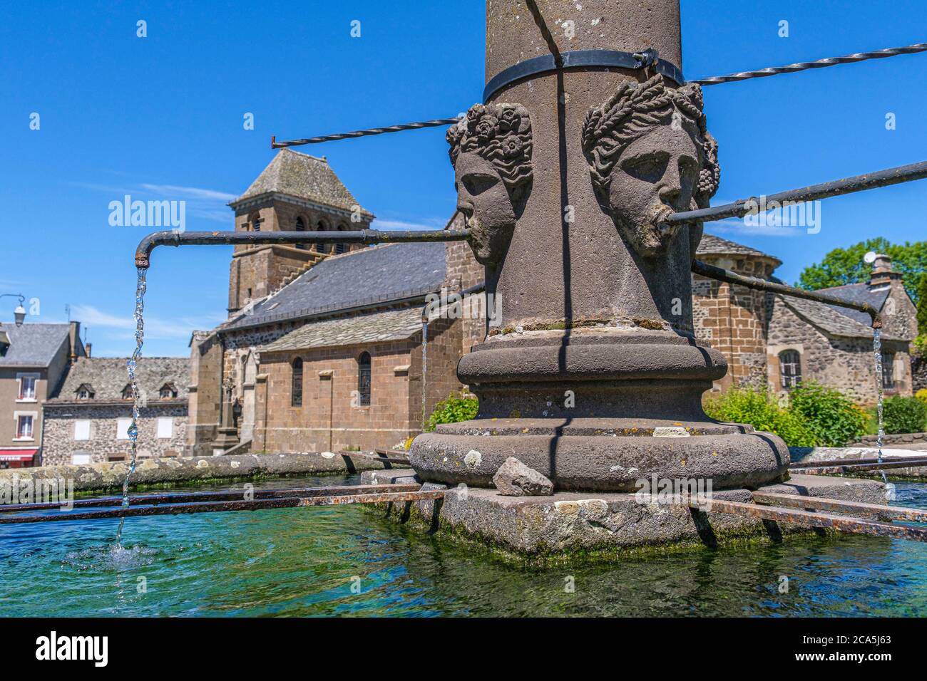 France, Cantal, fountain and church in the village of Trizac, regional ...
