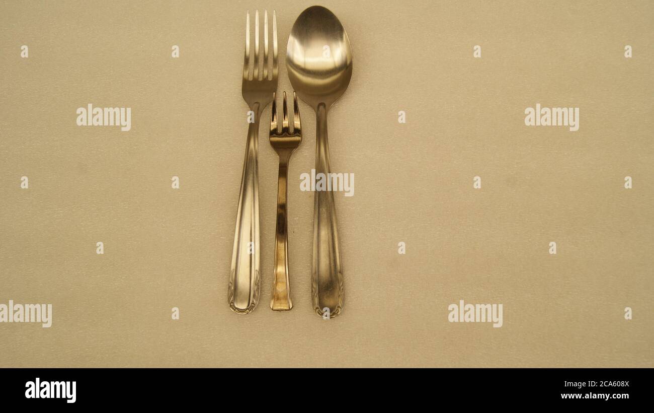 Large fork, small fork and spoon representing a family on white ...