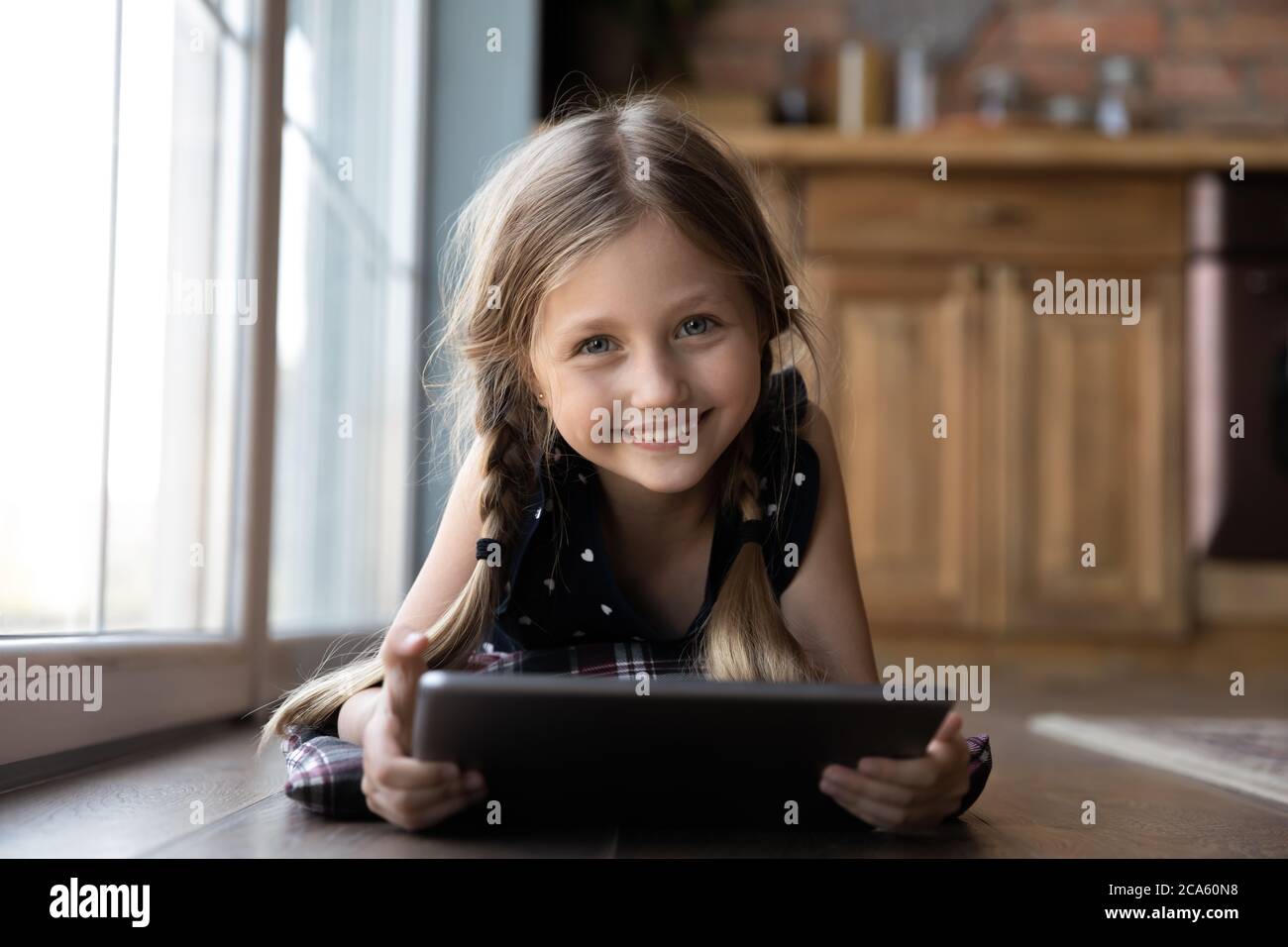 Portrait of smiling little girl using tablet on floor Stock Photo - Alamy