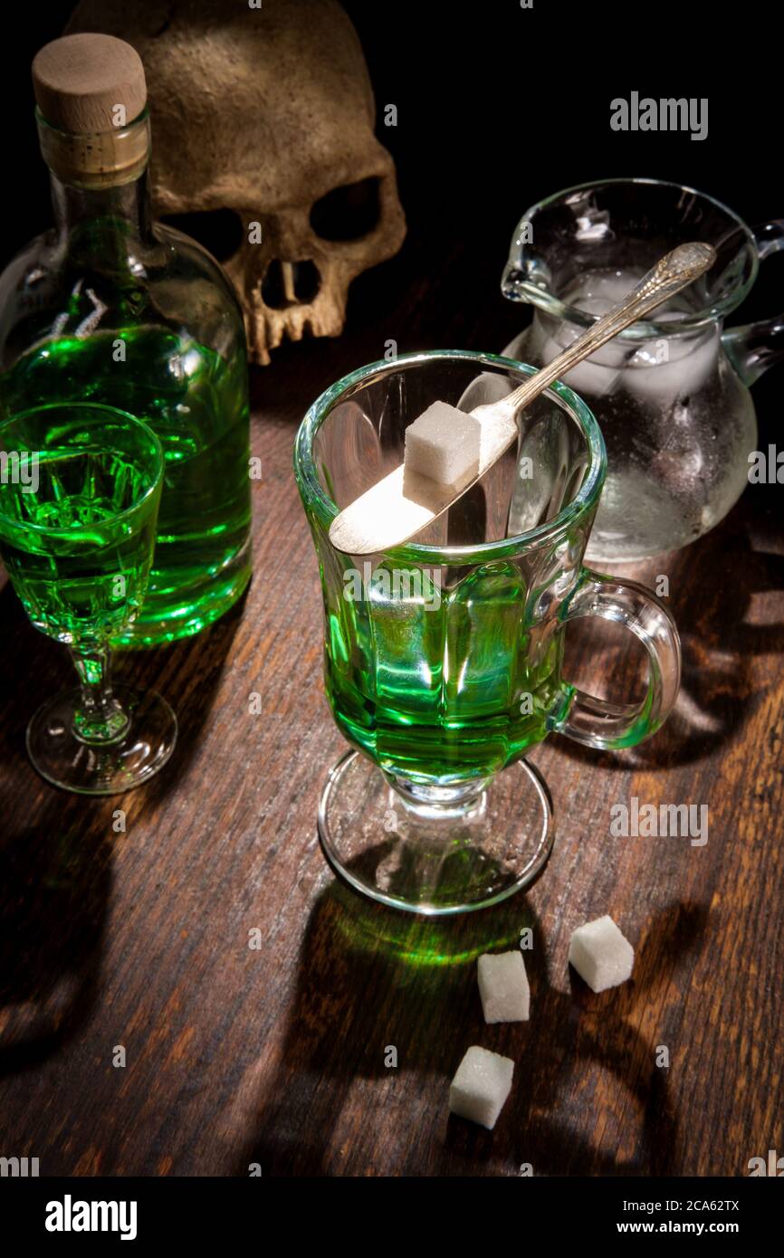 Green absinthe liquor in glass with ice water to pour over sugar cube ...