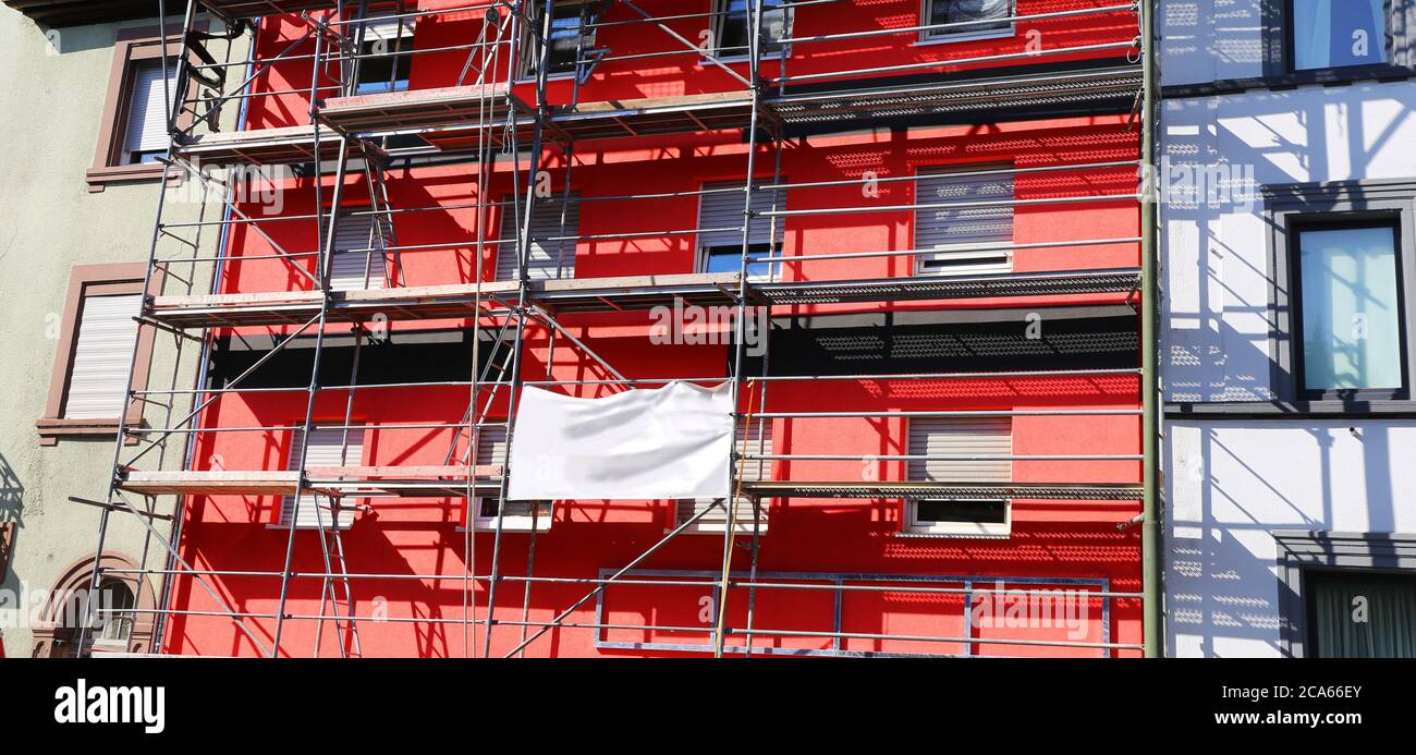 Old building is given a new red facade painting Stock Photo - Alamy