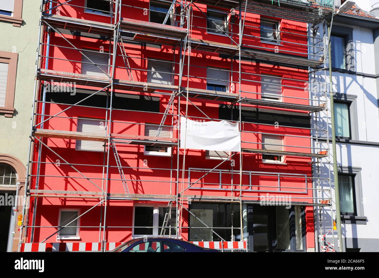 Old building is given a new red facade painting Stock Photo - Alamy