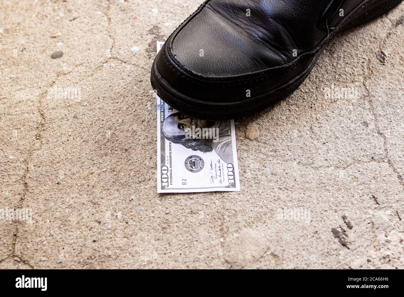 One hundred dollar bill under the shoe Stock Photo - Alamy