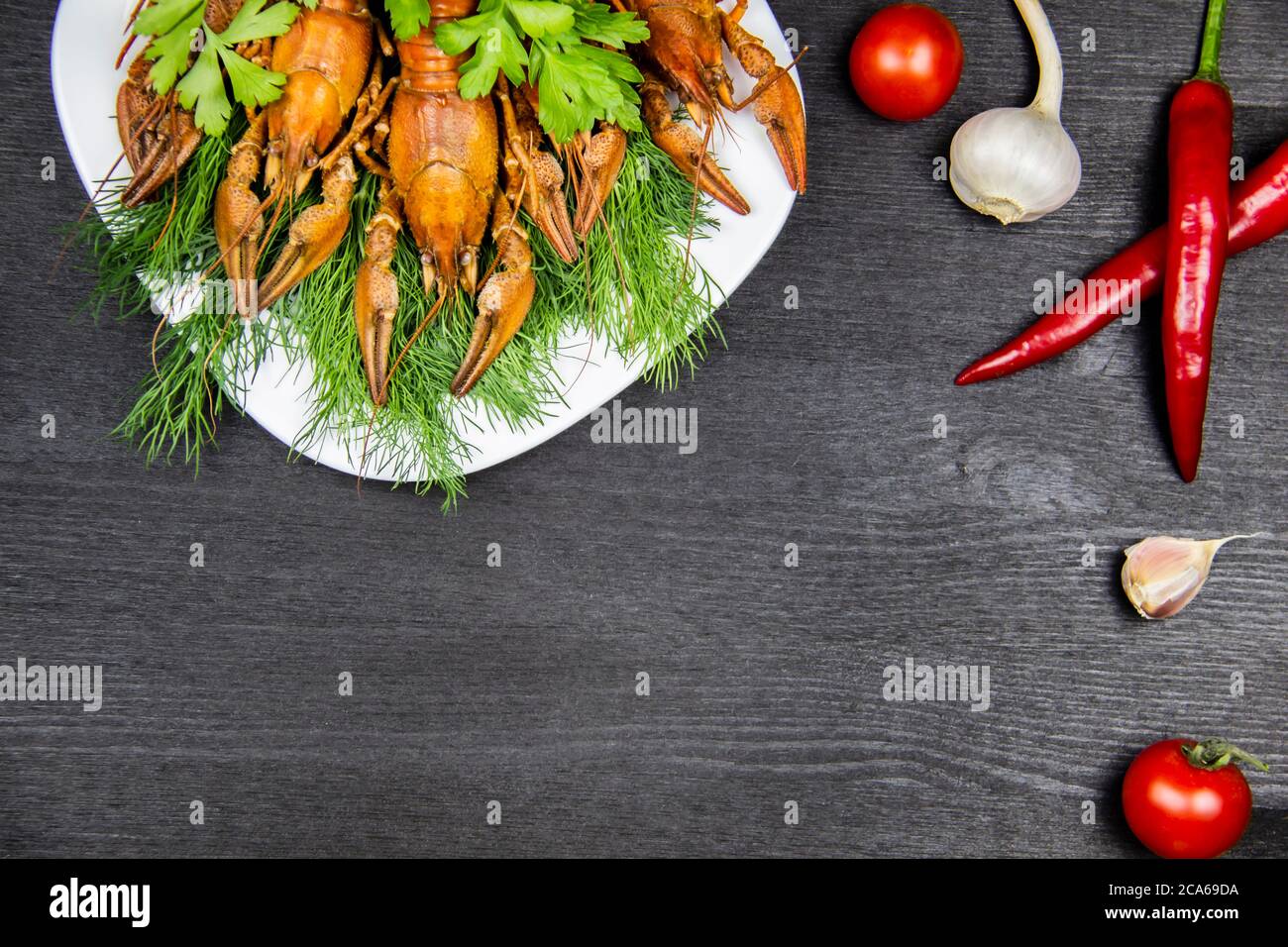 Red boiled crawfish on a white plate with a dill and parsley on the ...