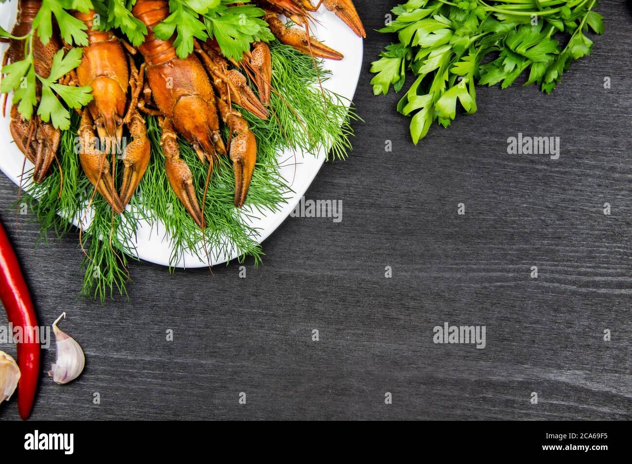 Red boiled crawfish on a white plate with a dill and parsley on the ...