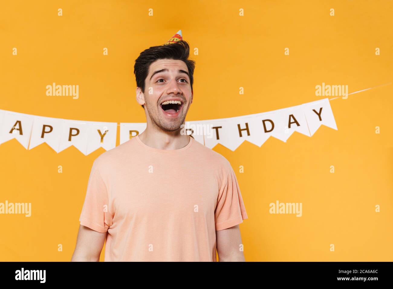 Photo of excited young man in party cone expressing surprise on camera ...