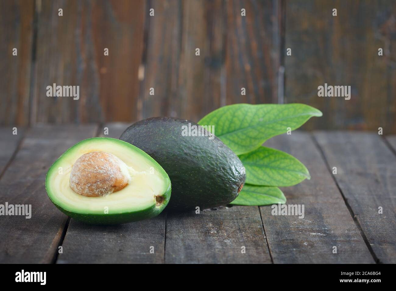 Avocado with leaves on wooden table. Ripe, nutritious avocados full of ...