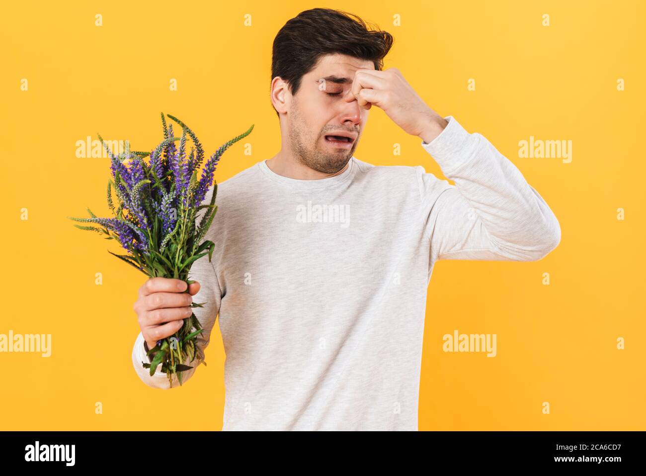 Photo of handsome unhappy man with allergy posing with flowers isolated ...