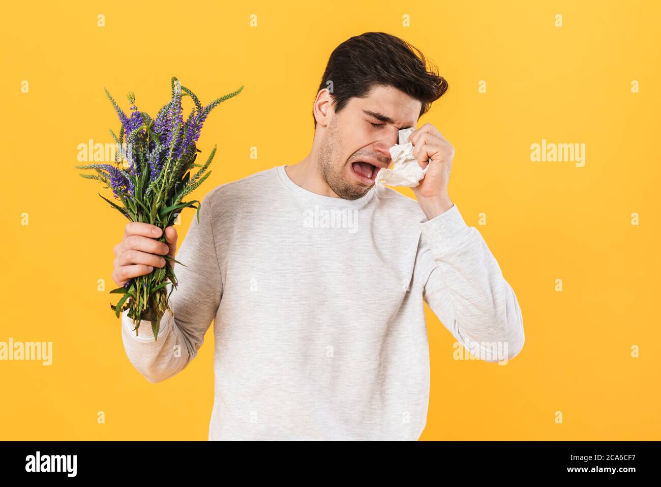 Photo of handsome unhappy man with allergy posing with flowers isolated ...