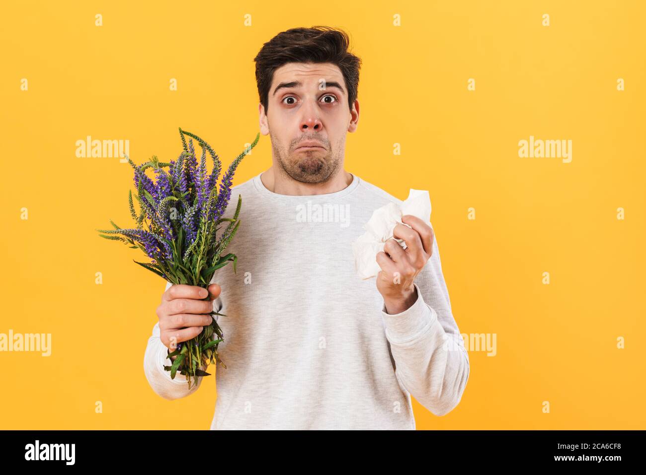 Photo of handsome unhappy man with allergy posing with flowers isolated ...