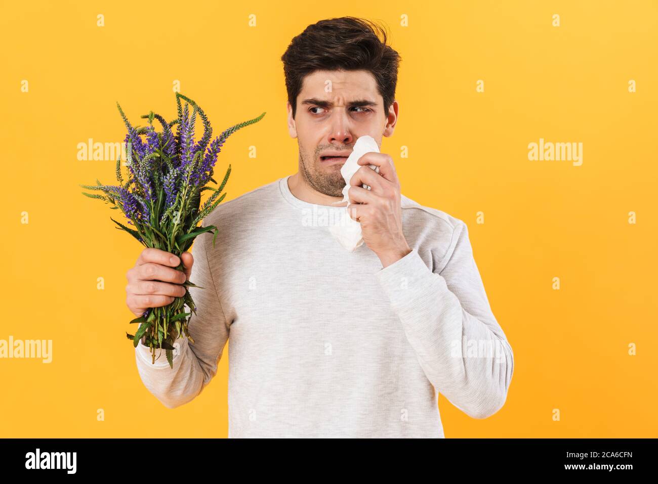 Photo of handsome unhappy man with allergy posing with flowers isolated ...