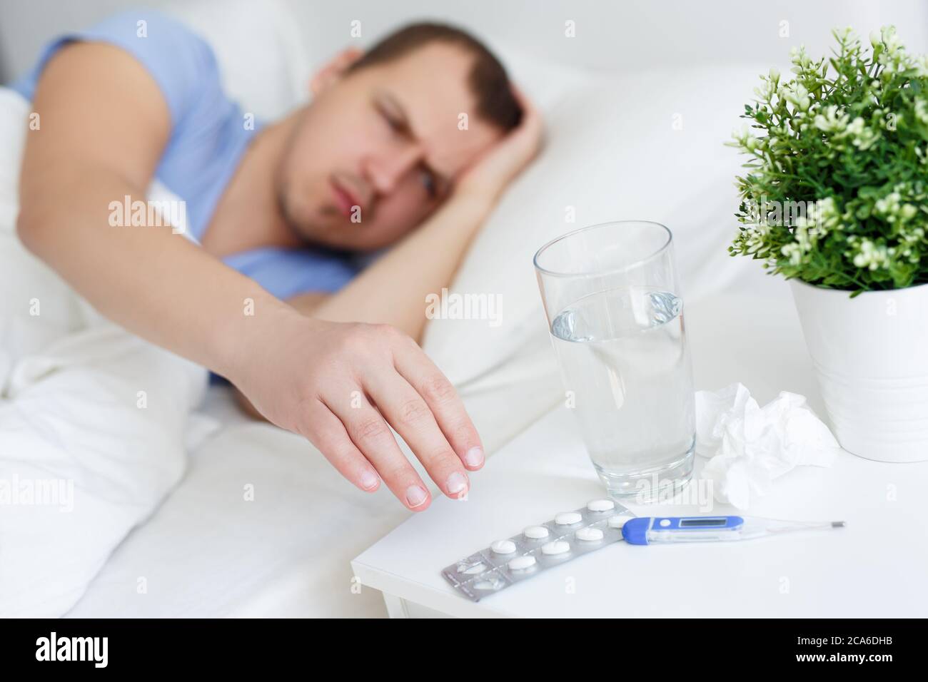 health care and illness concept - sick man with fever taking pills or ...