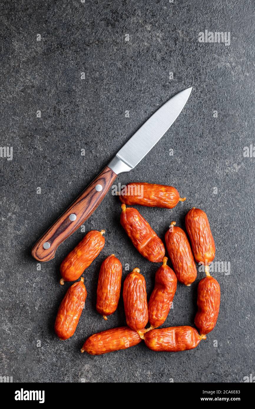 Mini salami sausages and knife on black table. Top view Stock Photo - Alamy