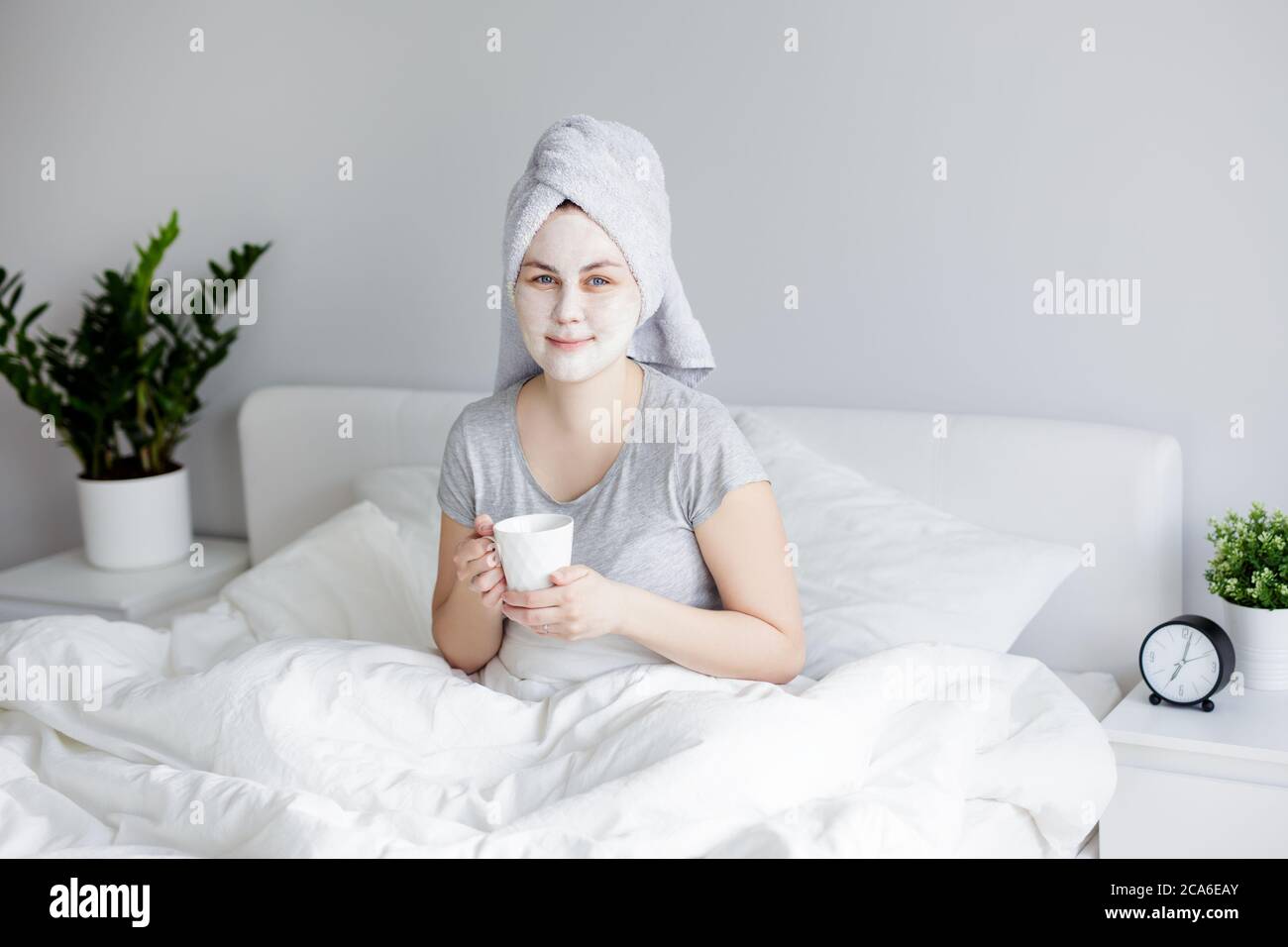 good morning and skin care concept - young woman with facial mask ...
