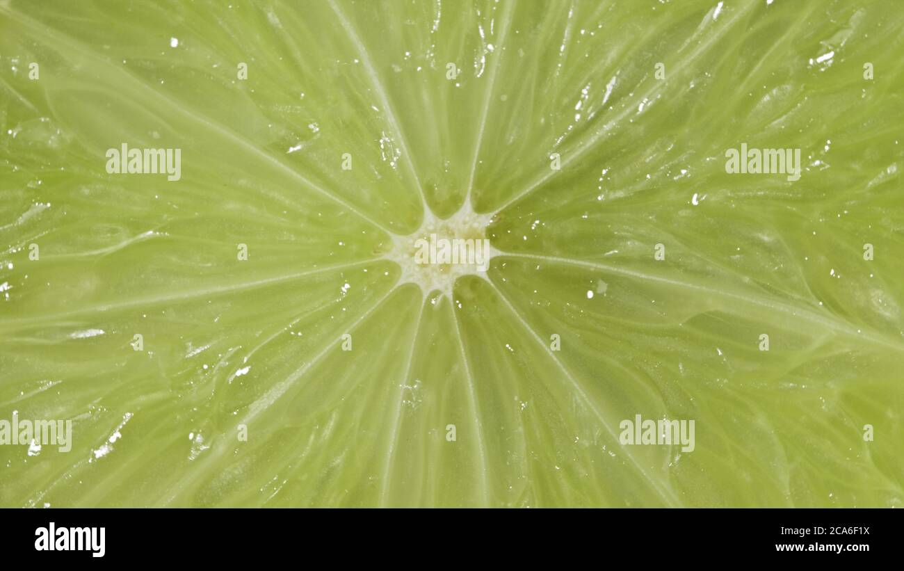Macro view of lime slice rotation. Extreme closeup of green juicy texture of exotic fruit ...