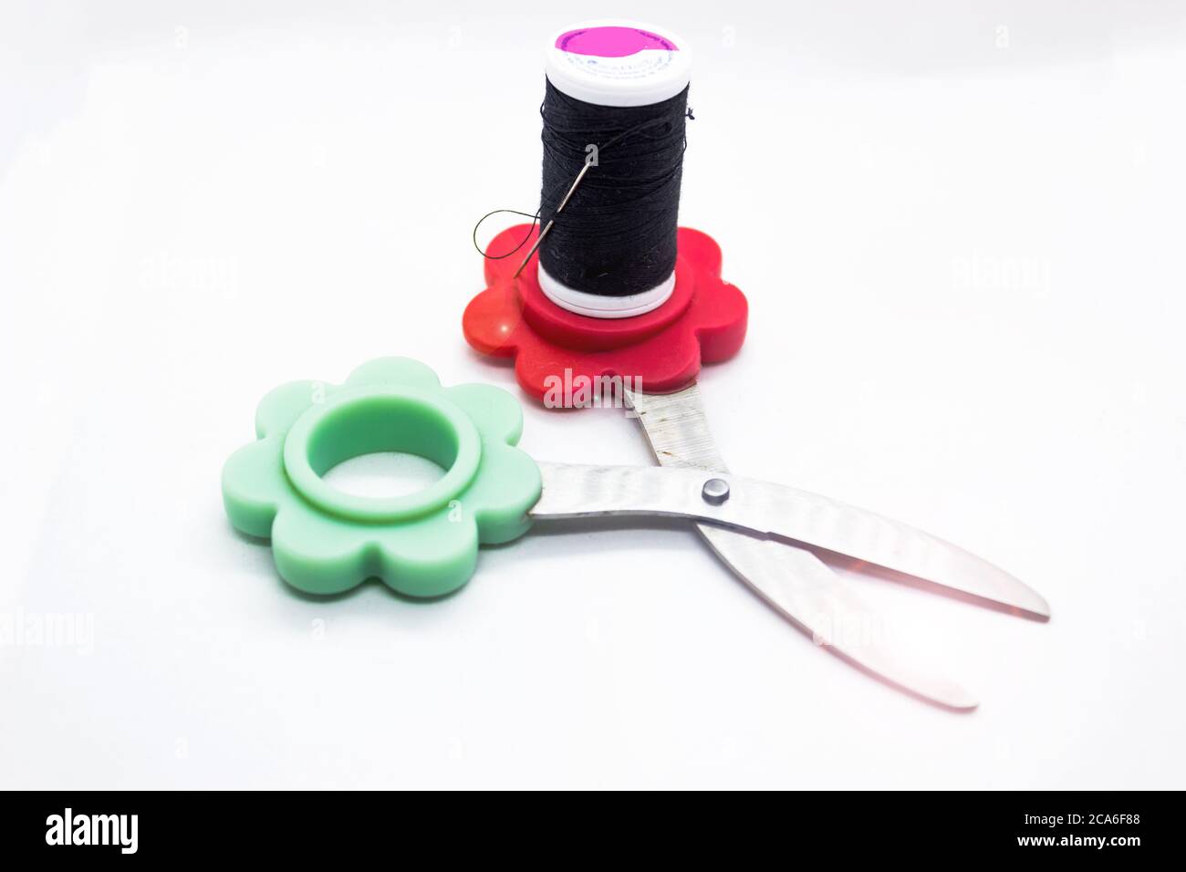 A needle, black thread and scissor for sewing against white background ...