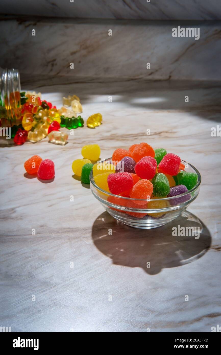 Granulated sugar coated candy gumdrops with spilled jar of gummy bears ...