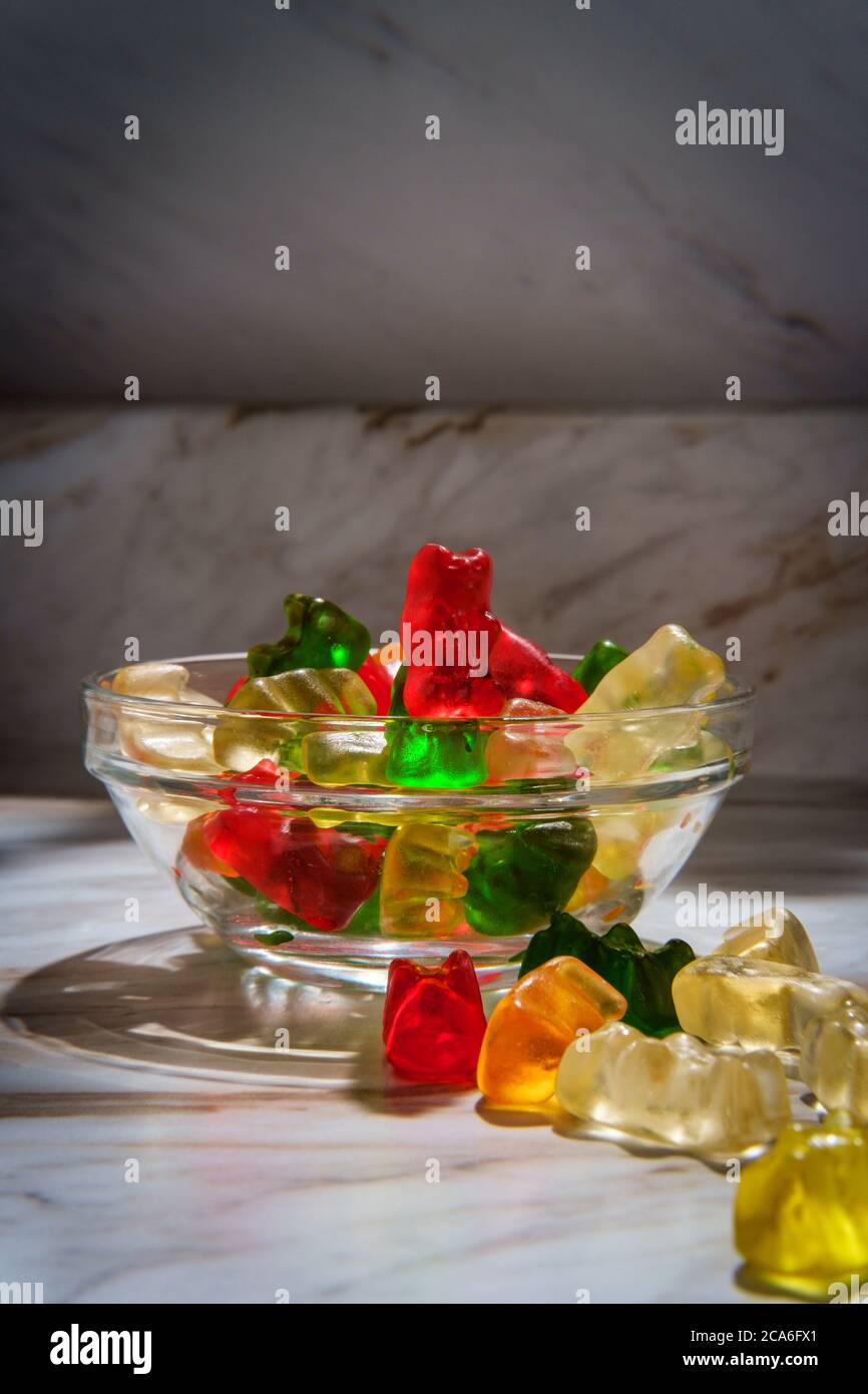 Assorted flavors of gummy bear candies in glass dish on marble kitchen ...