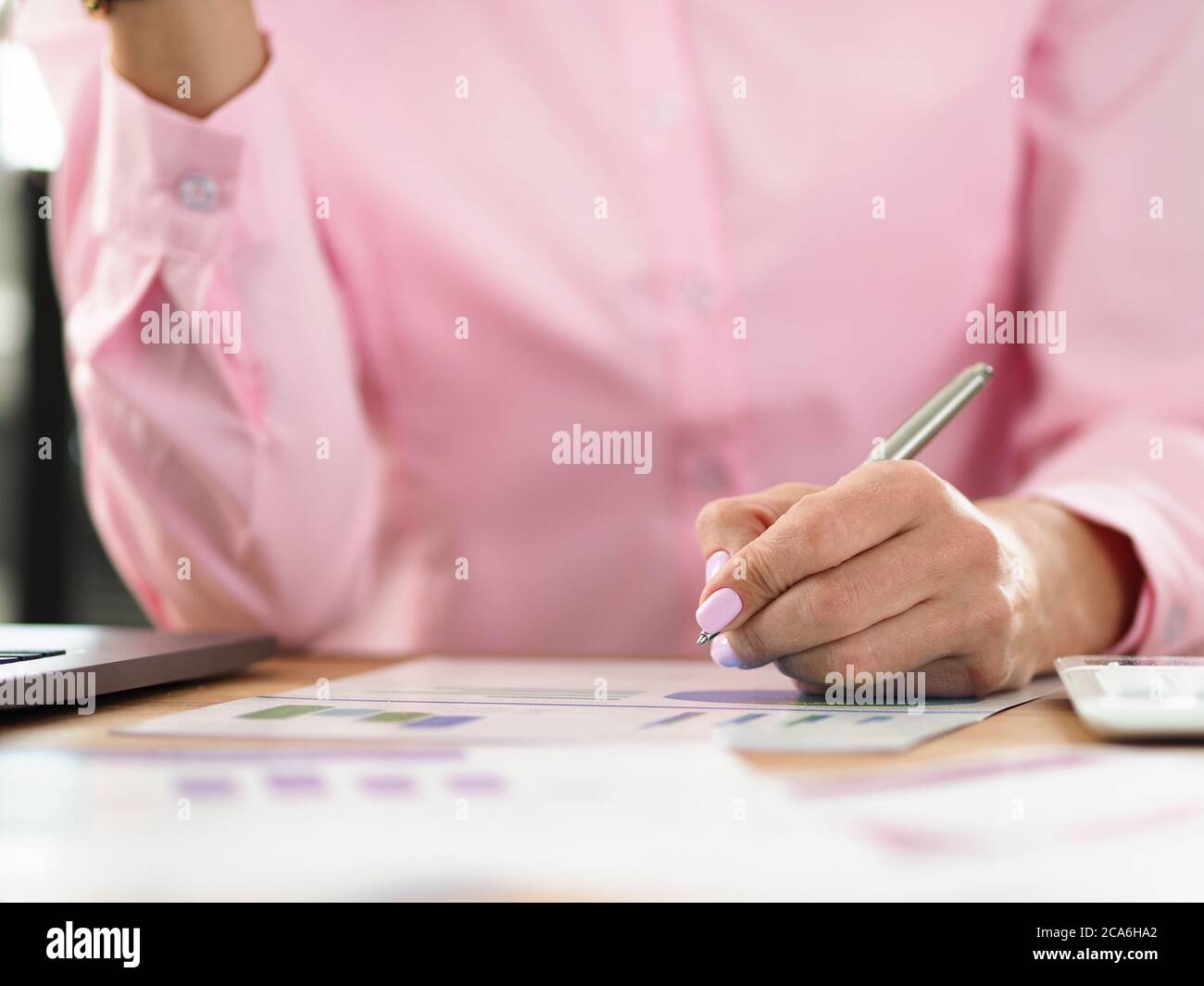 Woman sits at workplace and takes notes on chart Stock Photo - Alamy