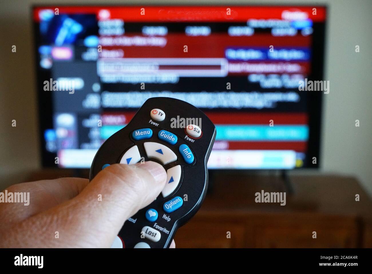 Hand using a TV remote control with the television out of focus Stock ...