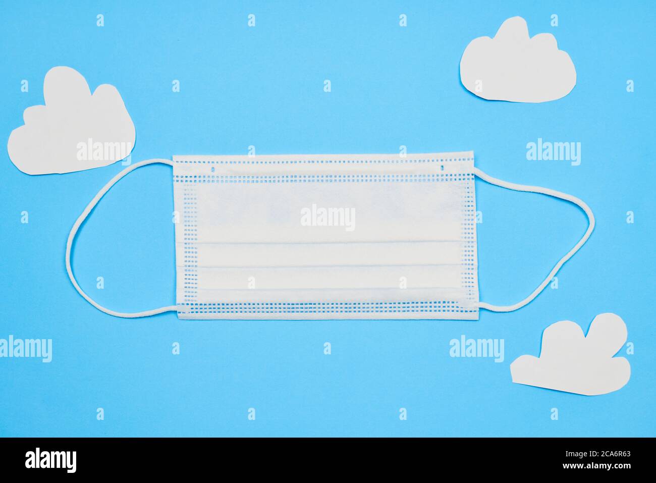 A face mask with paper clouds on the blue background. Safe cloud ...