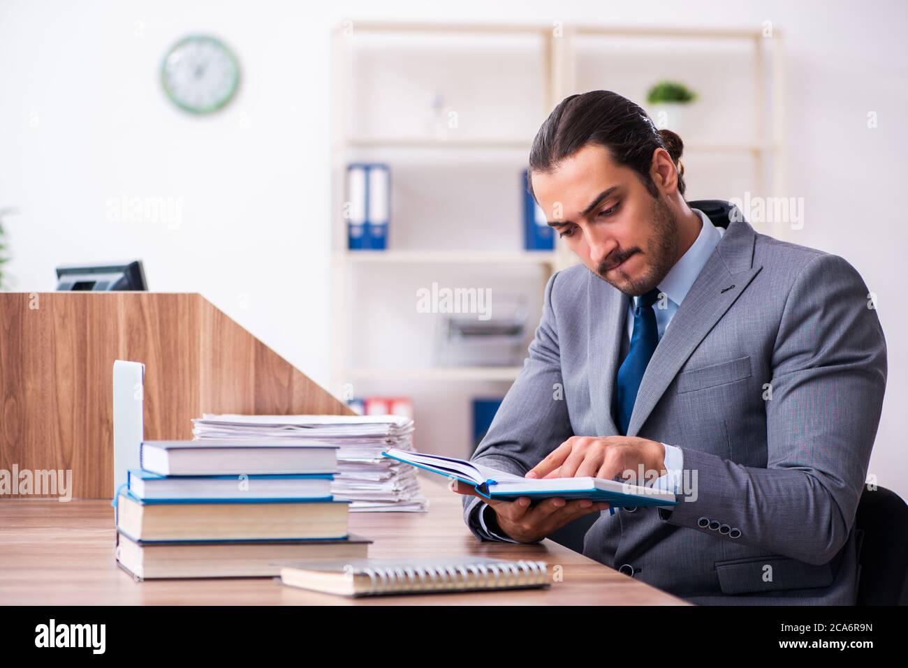 Young businessman reading books at workplace Stock Photo - Alamy