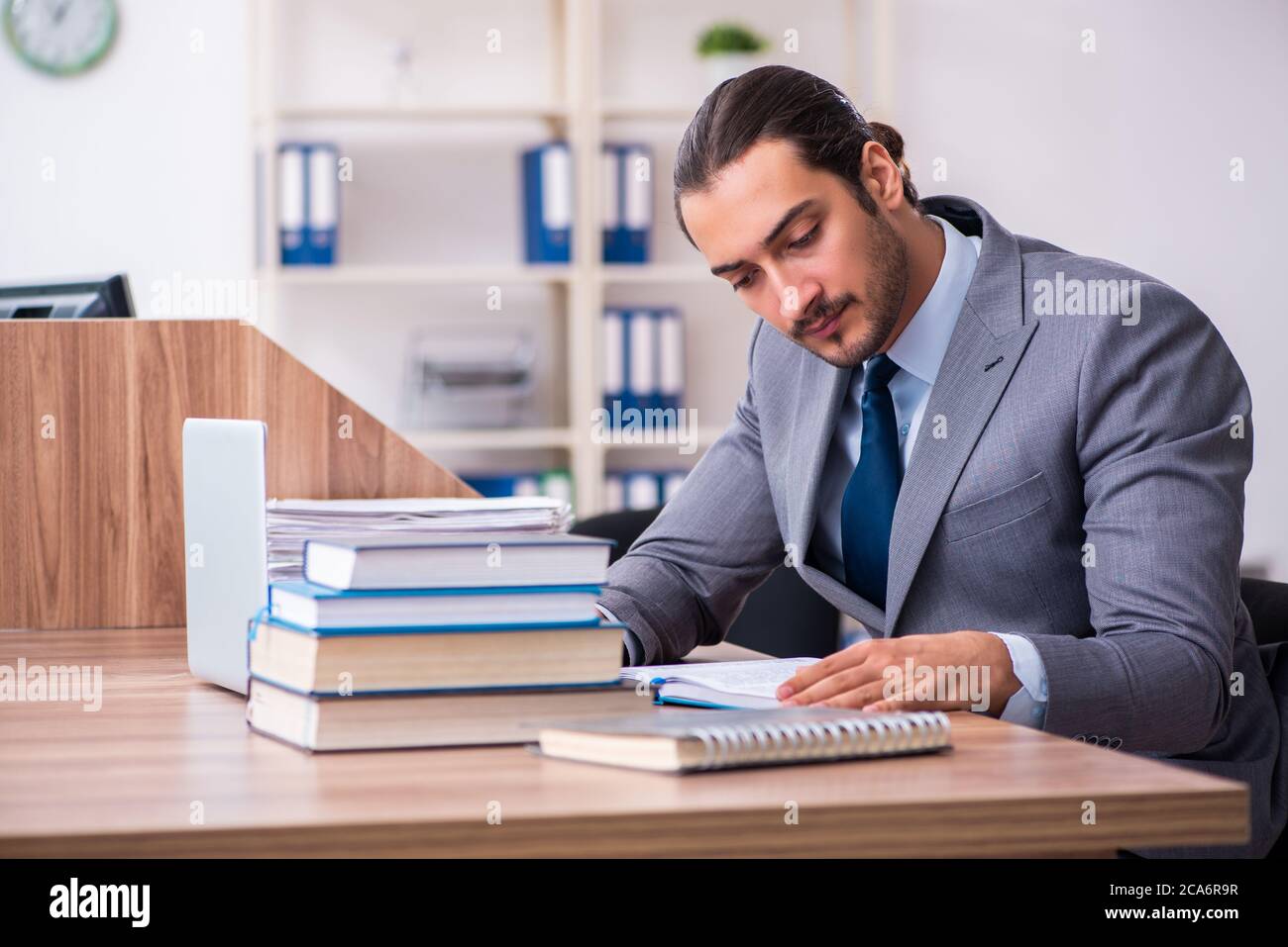 Young businessman reading books at workplace Stock Photo - Alamy