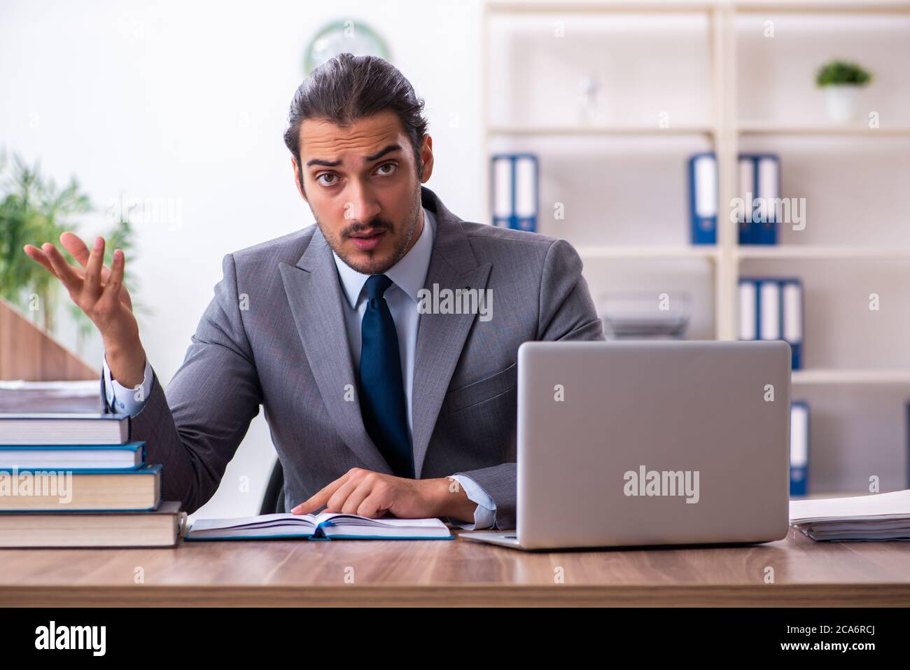 Young businessman reading books at workplace Stock Photo - Alamy