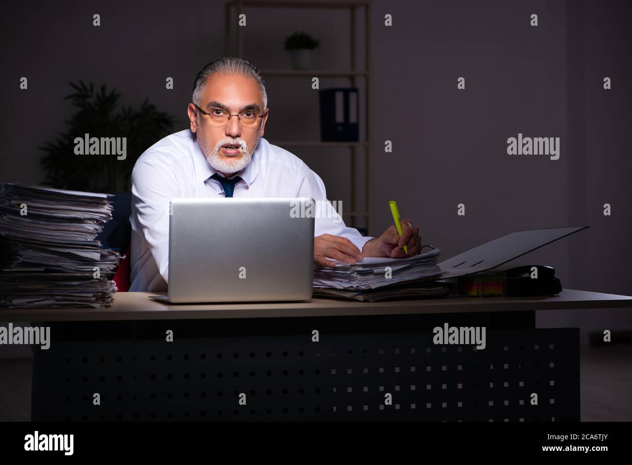 Old male employee working late at the workplace Stock Photo - Alamy