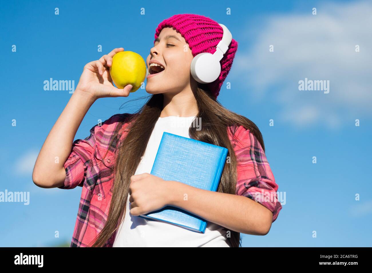 Taking snack break on fresh air. Small kid bite apple on blue sky ...