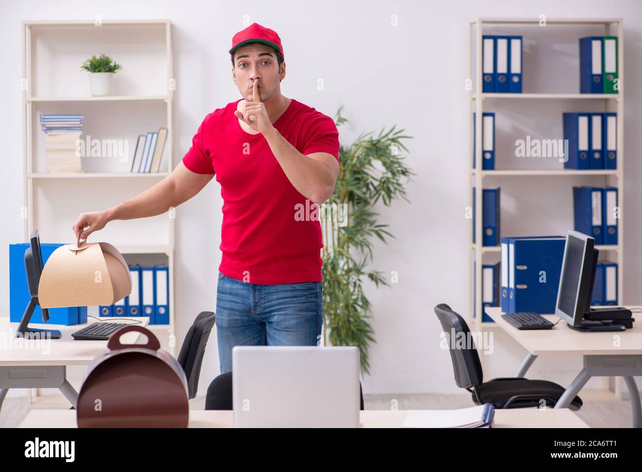 Young courier delivering cake to the office Stock Photo - Alamy