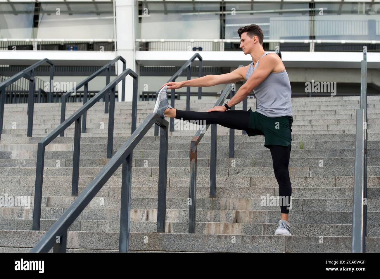 Determined Male Athlete Stretching Legs Outdoor Preparing For Workout