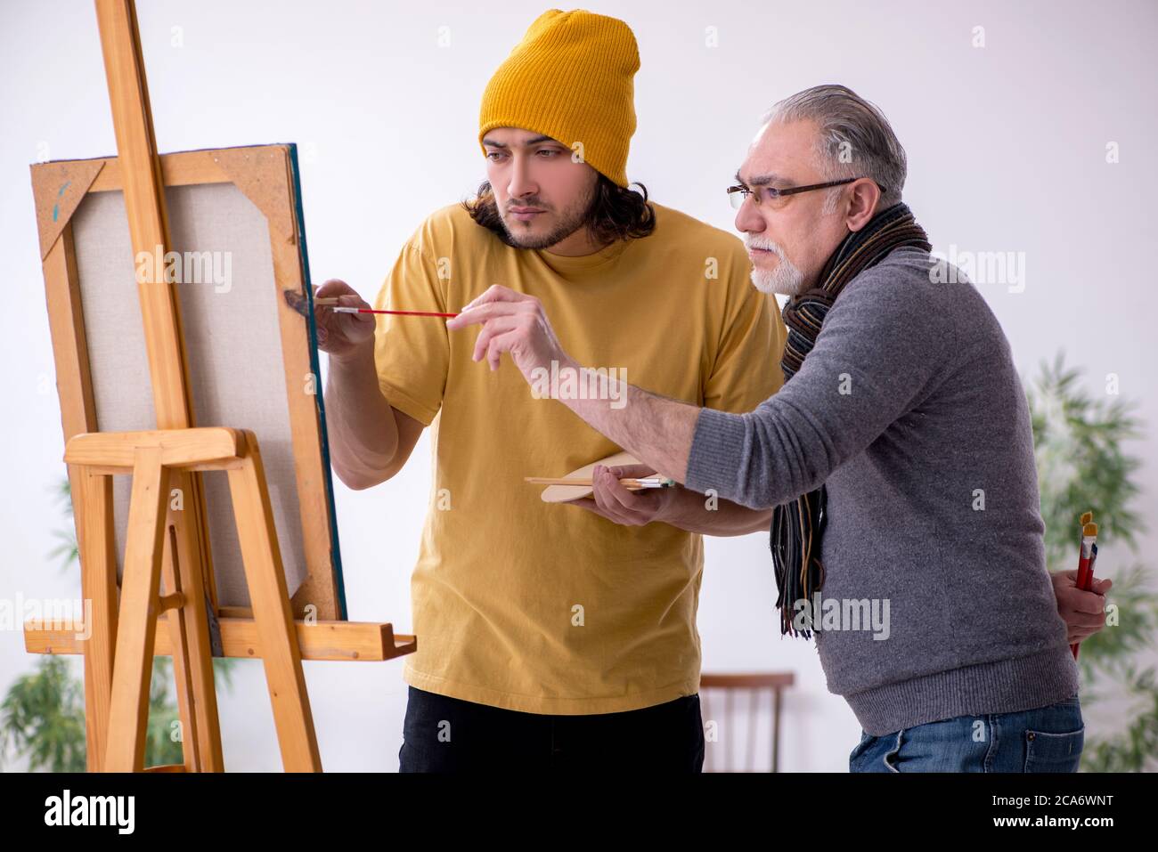 Old man taking lesson from younger painter Stock Photo - Alamy