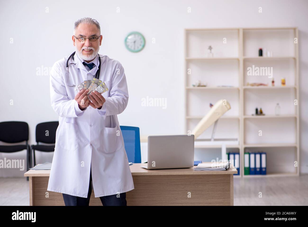 Old experienced doctor working in the clinic Stock Photo - Alamy